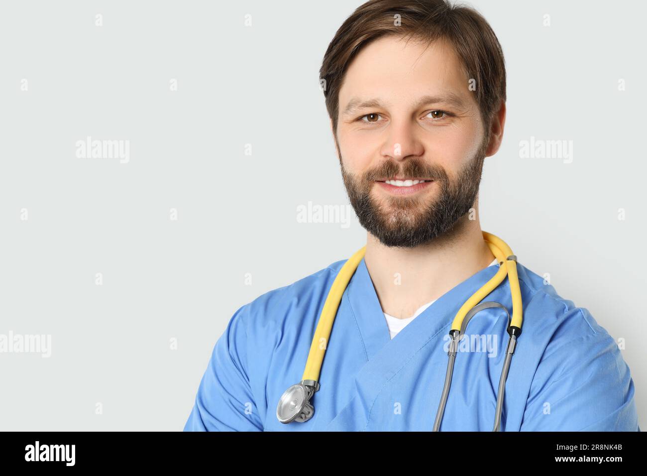 Doctor or medical assistant (male nurse) with stethoscope on light grey ...