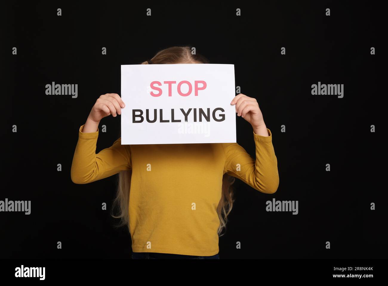 Girl holding sign with phrase Stop Bullying on black background Stock ...