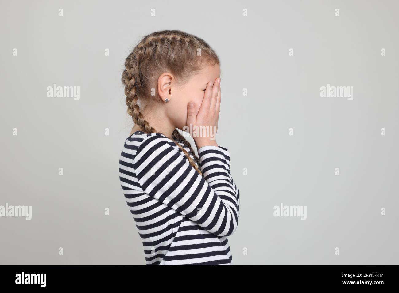 Girl covering face with hands on light grey background. Children's ...