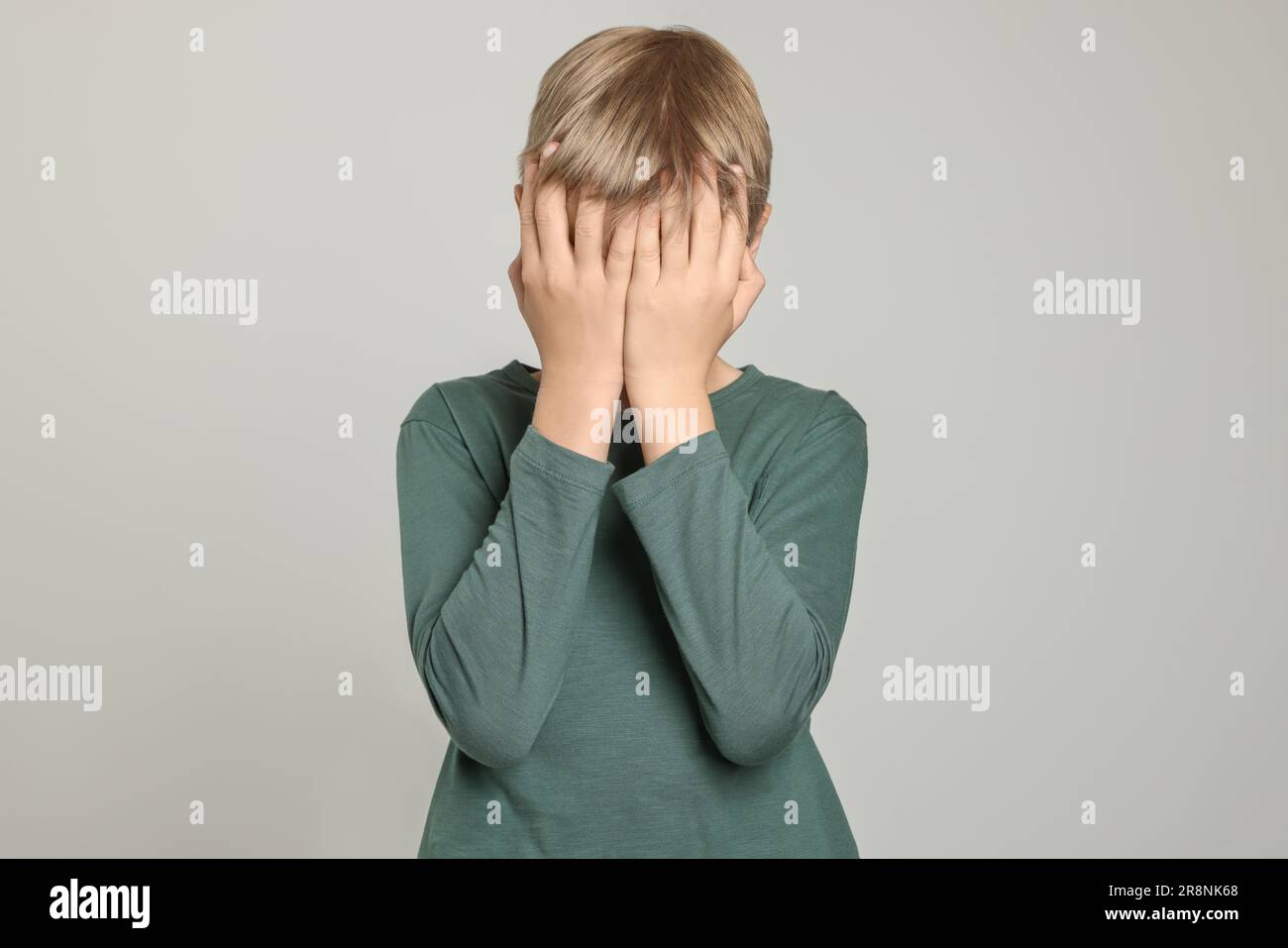 Boy covering face with hands on light grey background. Children's ...