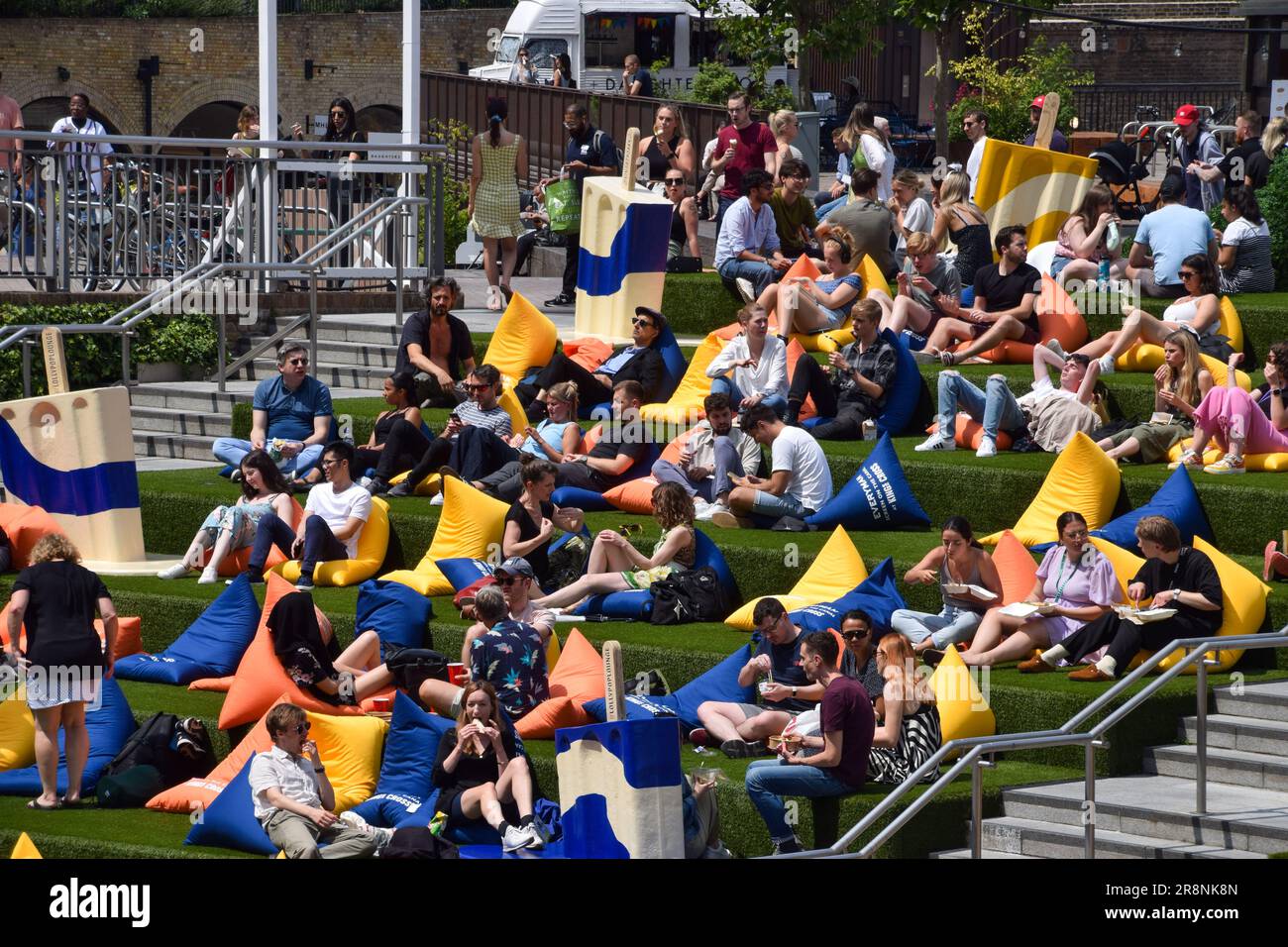 London, UK. 22nd June 2023. Crowds soak up the sun next to giant 'melting ice lollies' on the ...