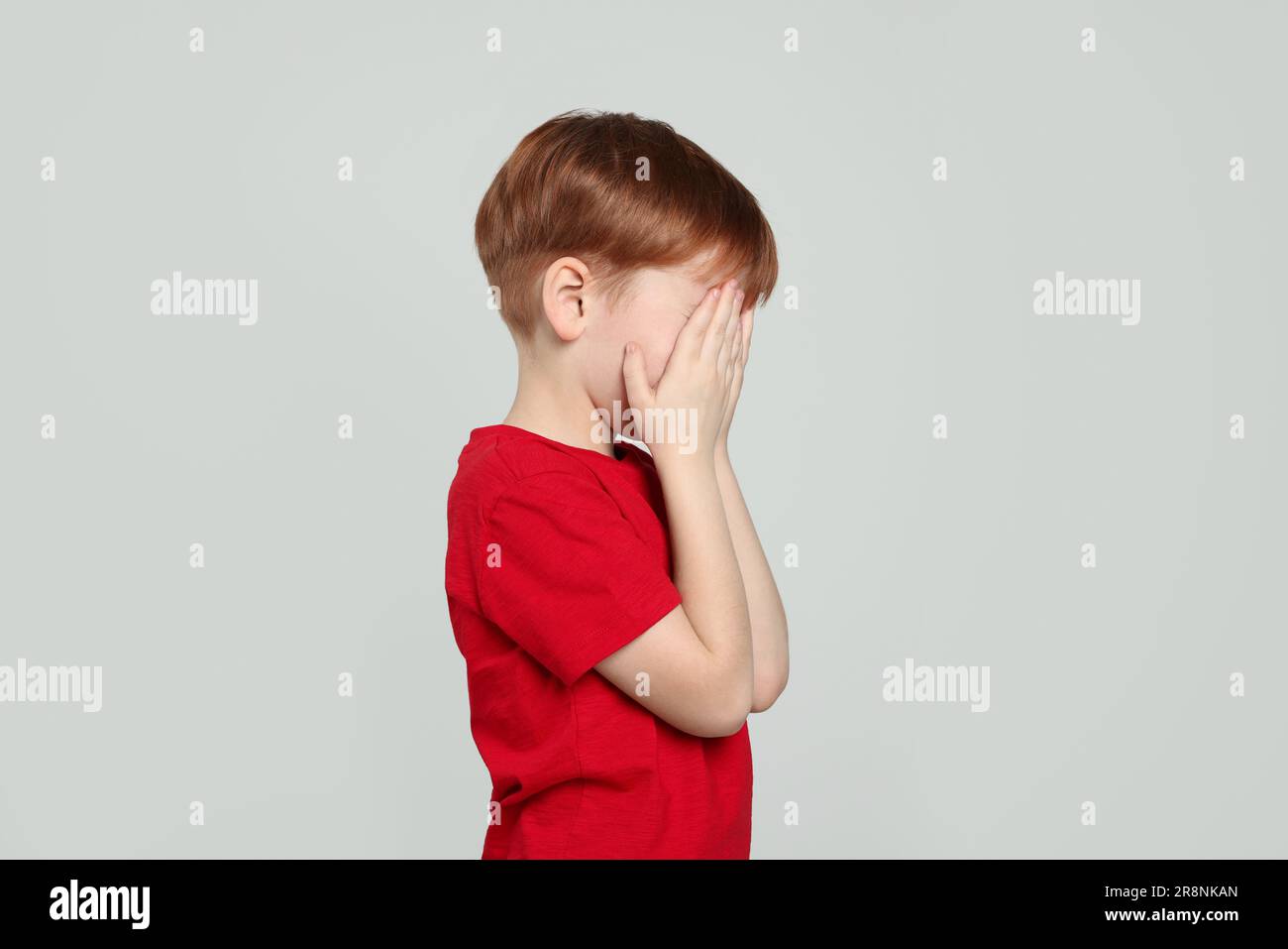 Boy covering face with hands on light grey background. Children's ...