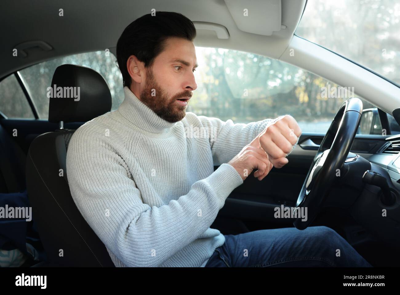 Emotional man checking time on watch in car. Being late concept Stock ...