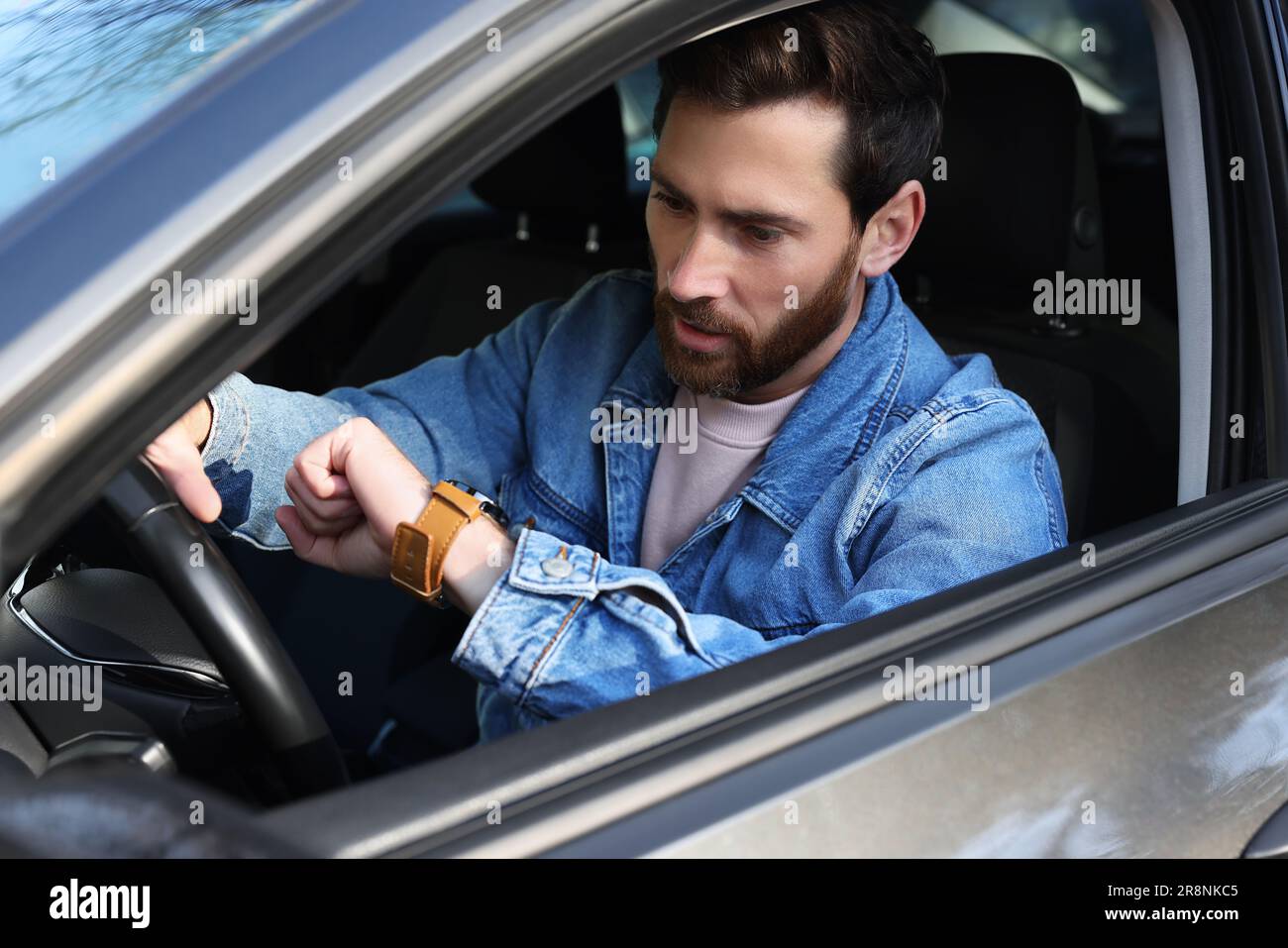 Emotional man checking time on watch in car. Being late concept Stock ...