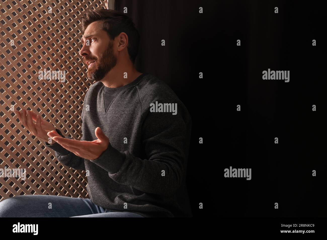 Upset man talking to priest during confession in booth, space for text ...