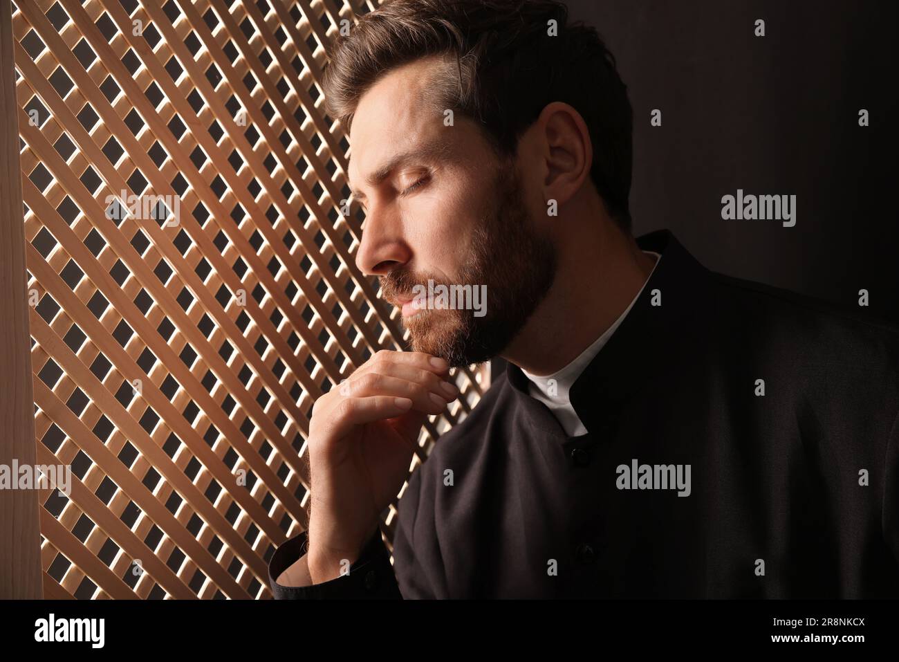 Catholic priest wearing cassock in confessional booth Stock Photo - Alamy
