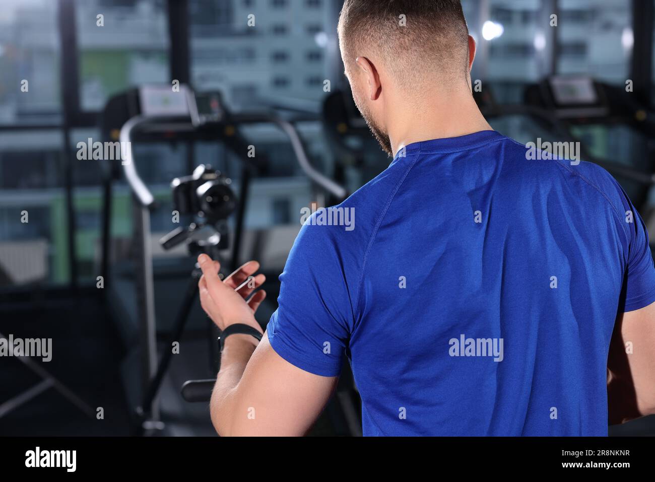 Man recording workout on camera at gym, back view. Online fitness ...