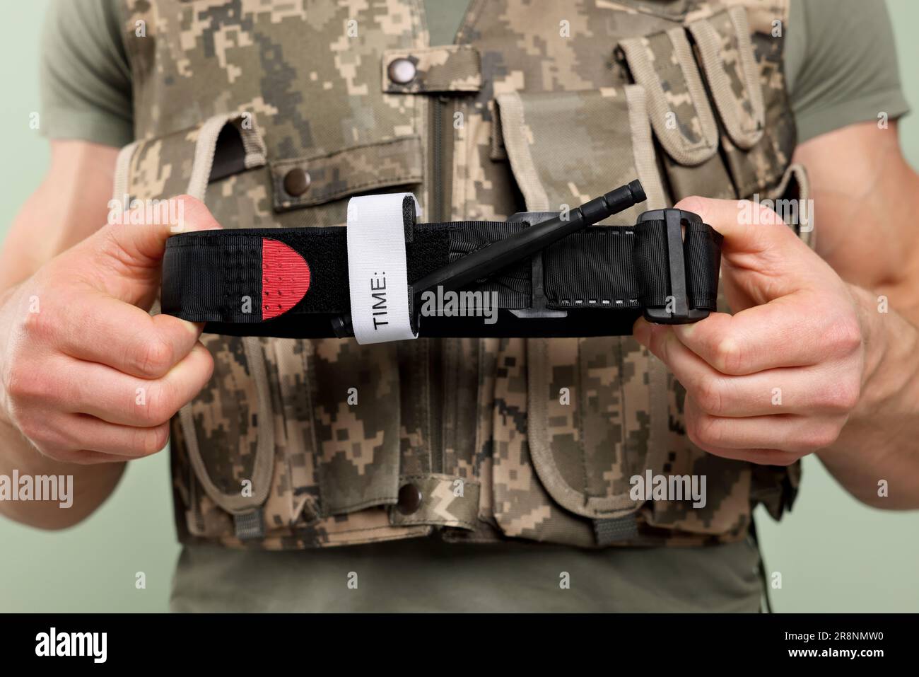 Soldier in military uniform holding medical tourniquet on light olive ...