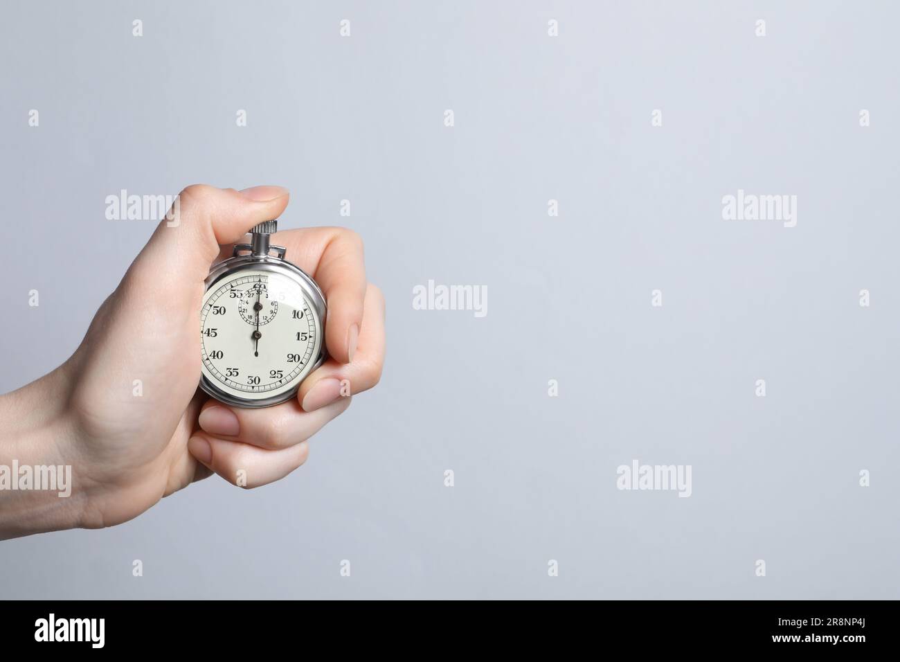Woman holding vintage timer on light grey background, closeup. Space ...