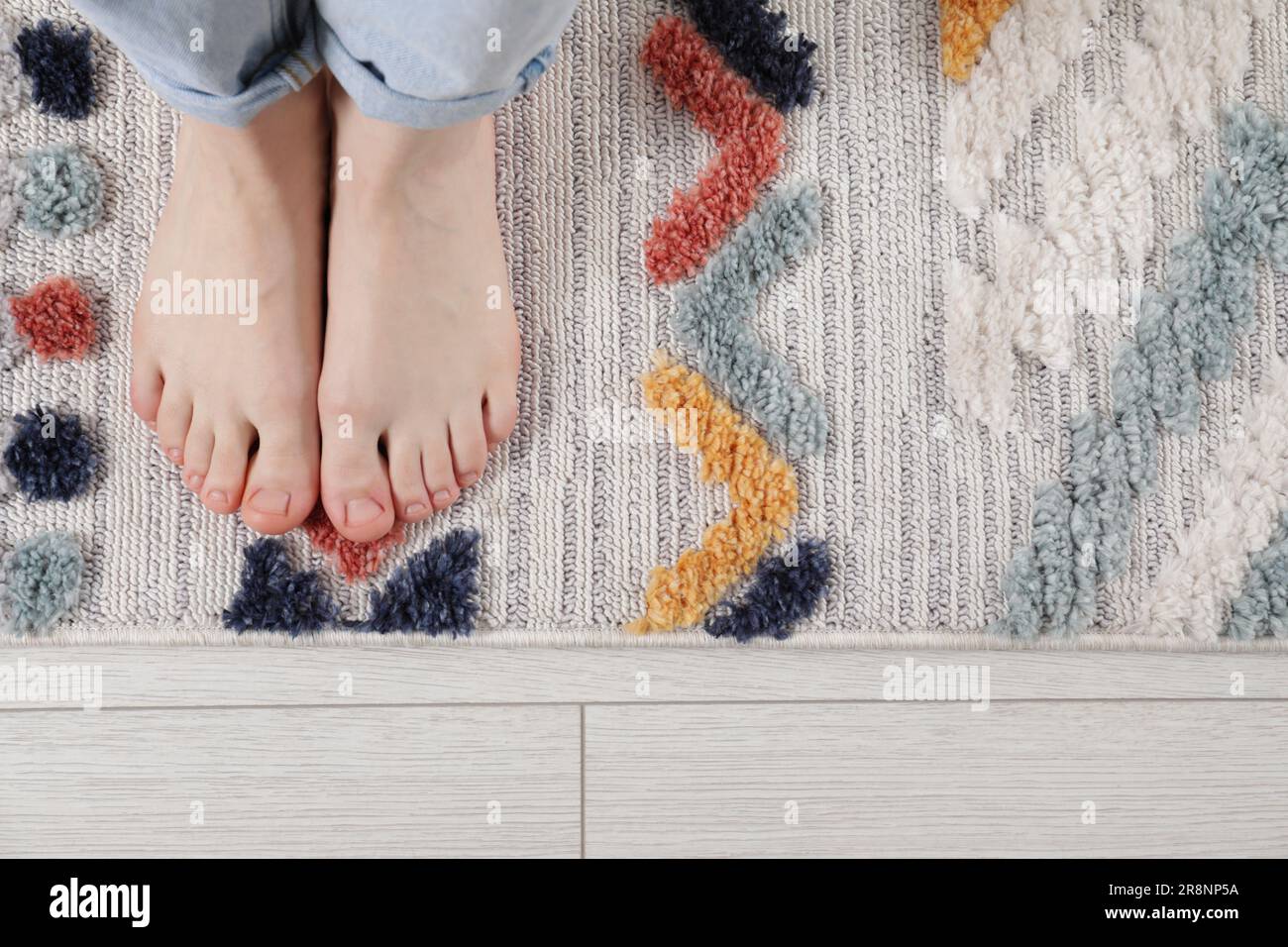 Woman standing on carpet with pattern at home, top view Stock Photo - Alamy
