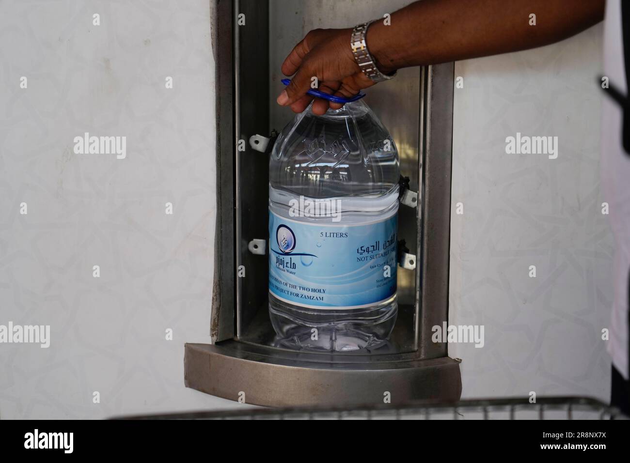 A man carries a bottle of Zamzam water, drawn from the well beneath the ...