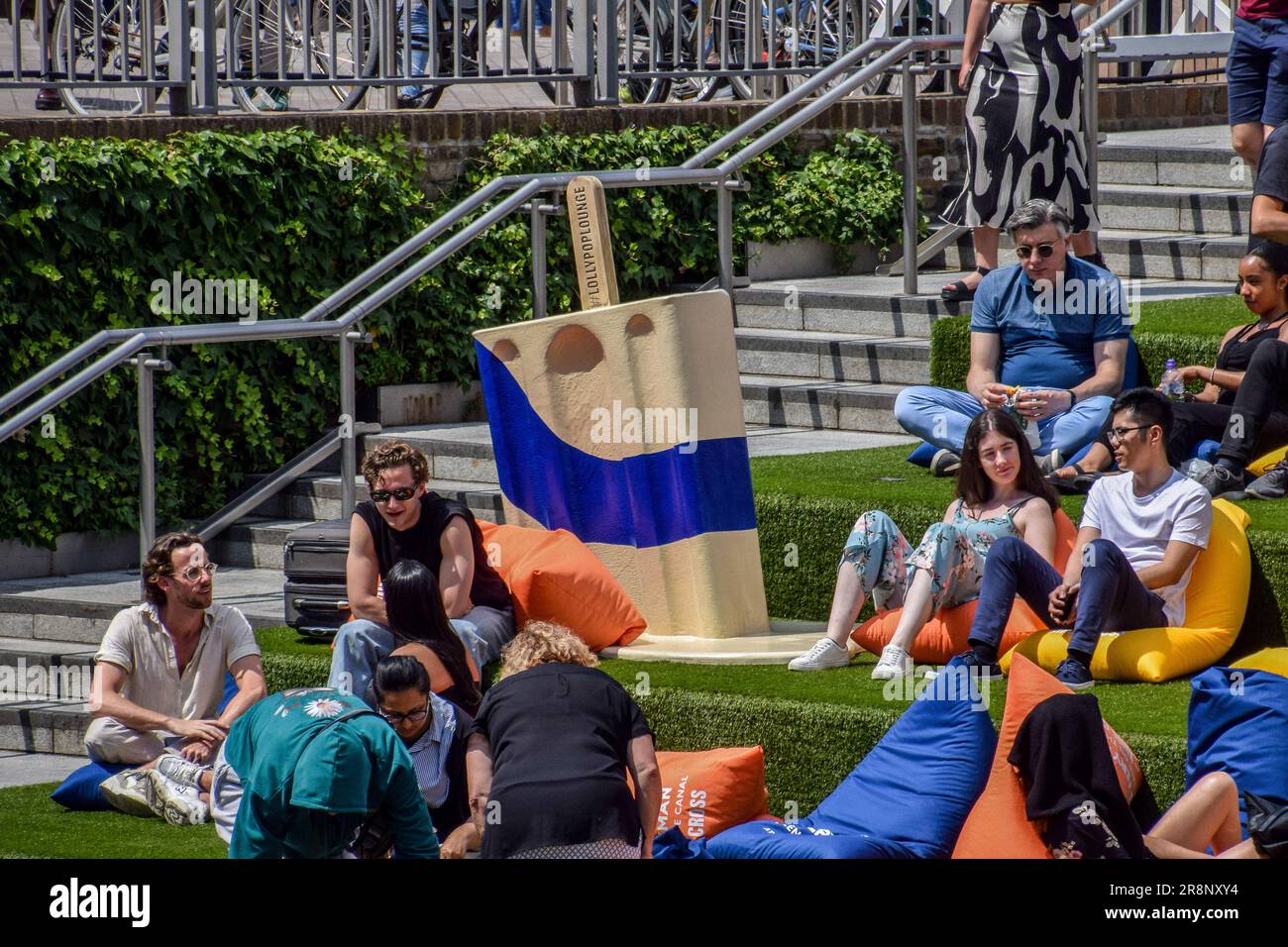 London, UK. 22nd June, 2023. People enjoy the sunshine next to giant ...