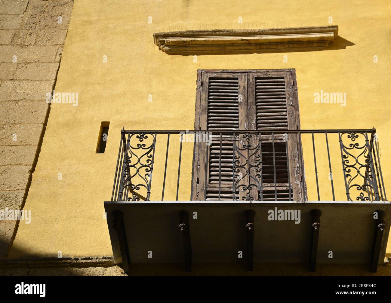 Old Neoclassical house facade with an ochre stucco wall, wooden window ...