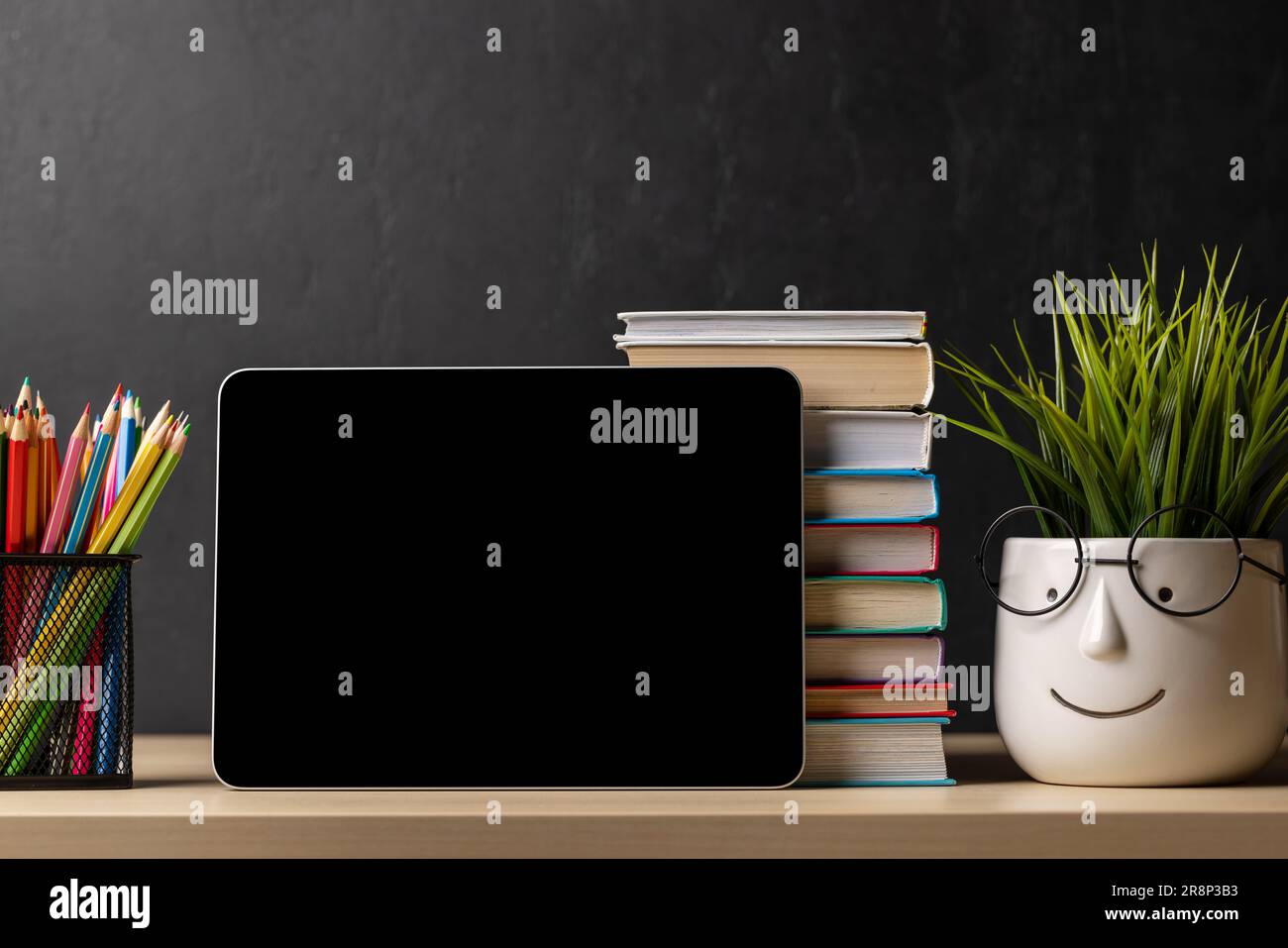 Tablet with colorful pencils and stack of books. With blank screen for ...