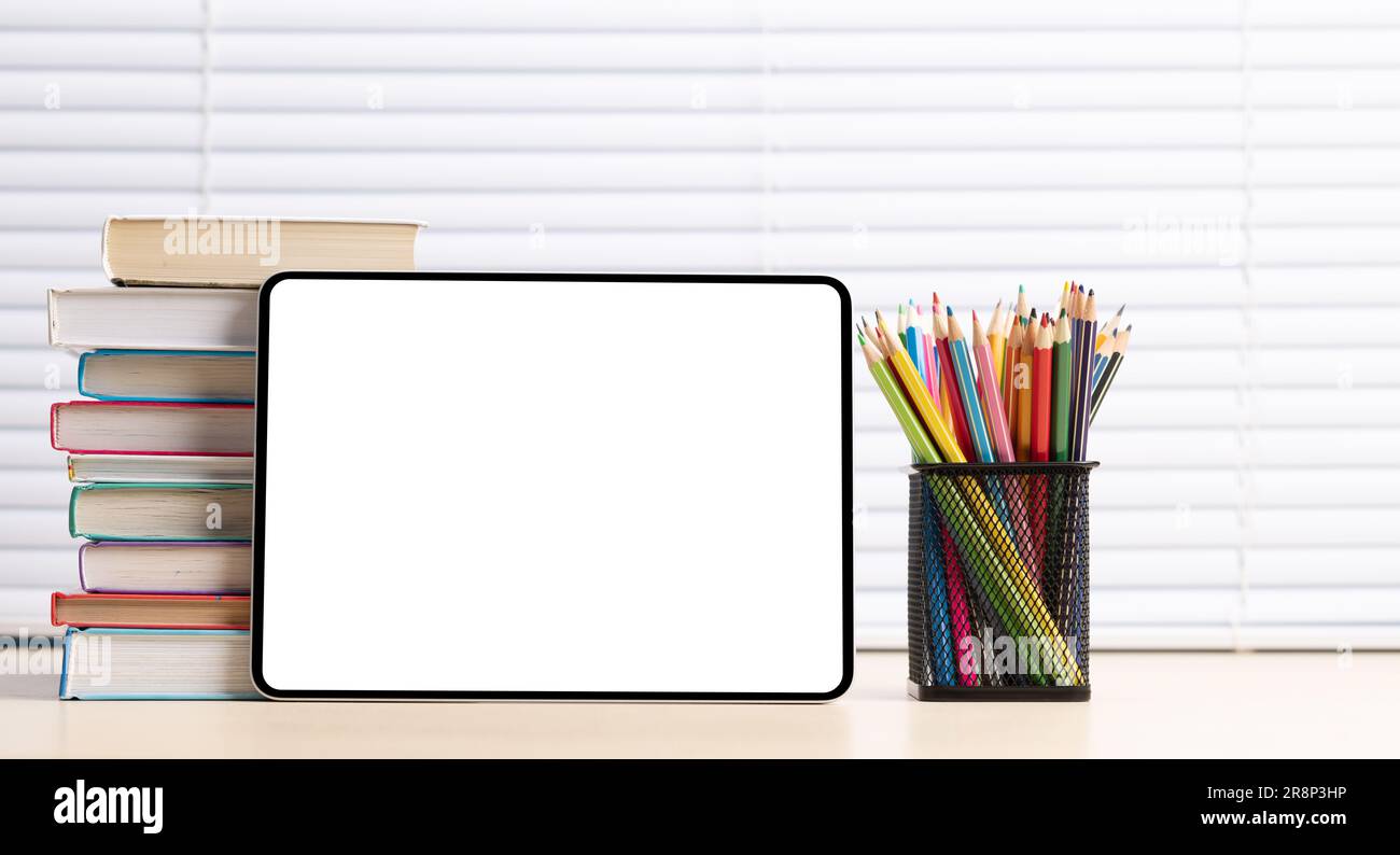 Tablet with colorful pencils and stack of books. With blank screen for ...