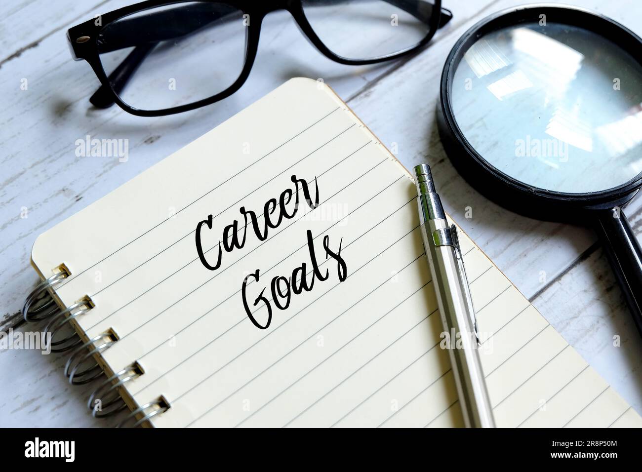 Magnifying glass,pen,sunglasses and notebook written with 'CAREER GOALS ...