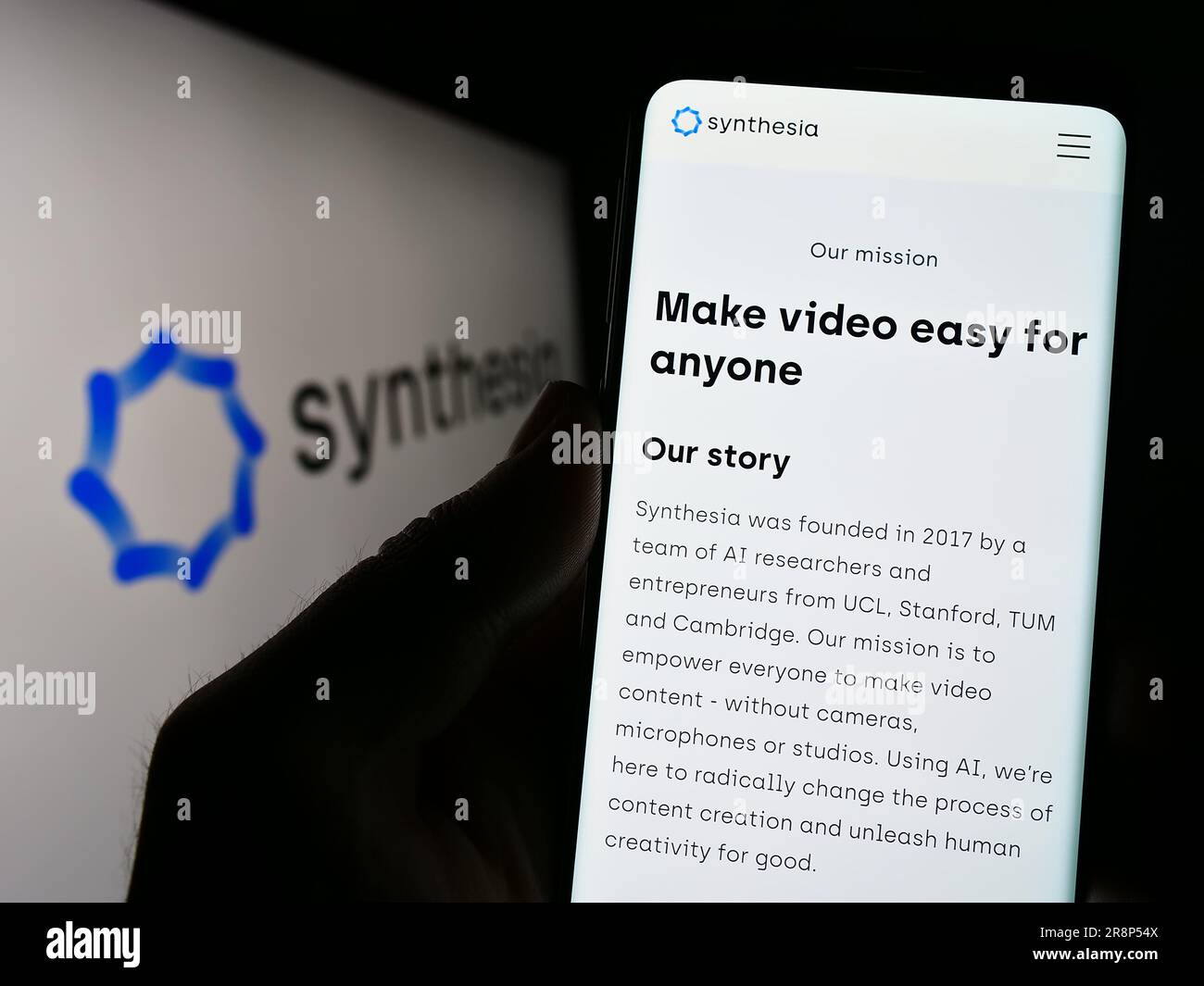 Person holding cellphone with webpage of British AI company Synthesia Limited on screen in front ...
