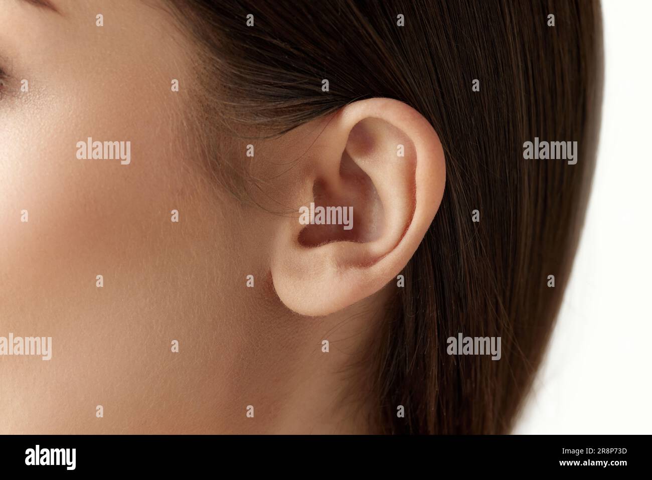 Close-up cropped image of female head part, ear against white studio ...