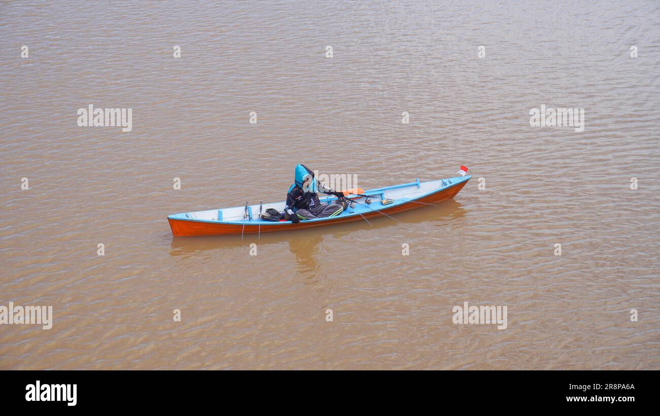 A fisherman with a small boat that floats in the middle of the river ...
