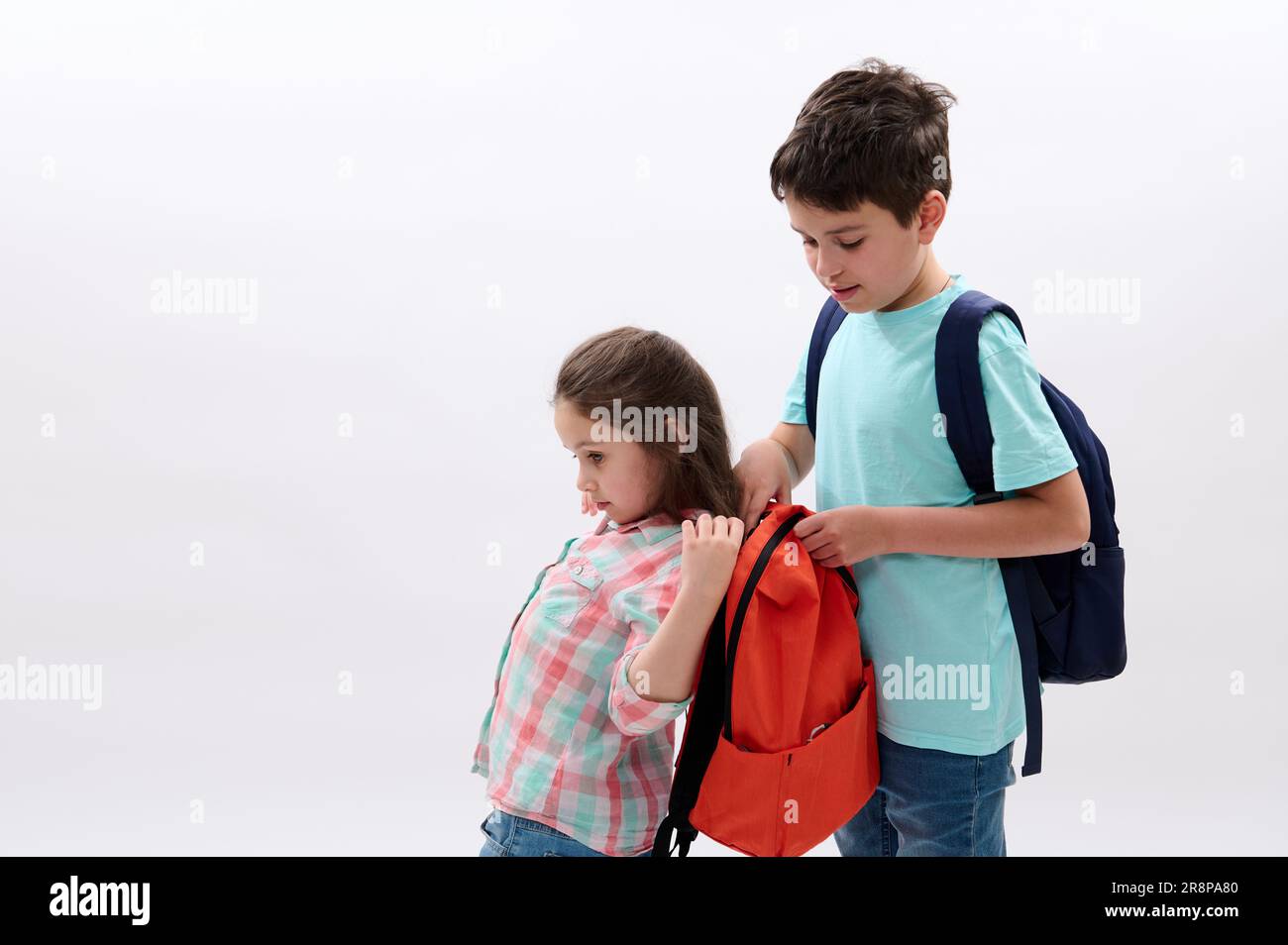 Caring teen boy older brother helps his younger sister to put on a ...