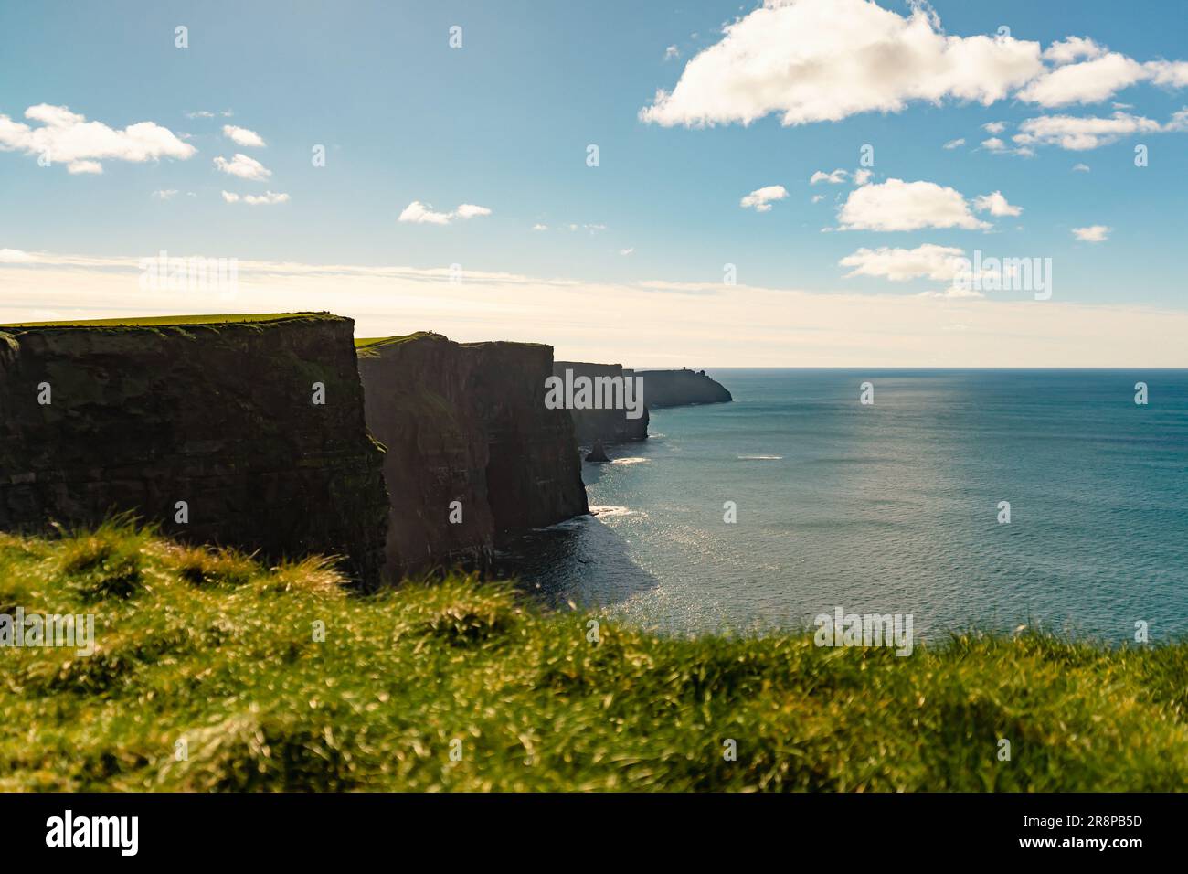 A scenic landscape featuring a rocky shoreline with blue ocean waters ...