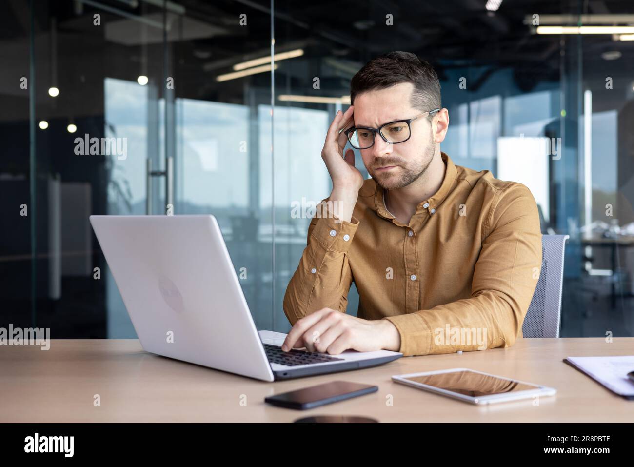 Problems at work. Pensive and serious male office worker, sitting at a ...