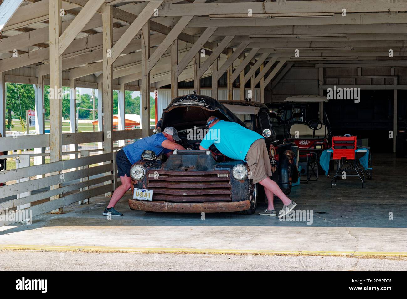 Two guys under the hood of an old vintage 1950s Chevy pick-up truck ...