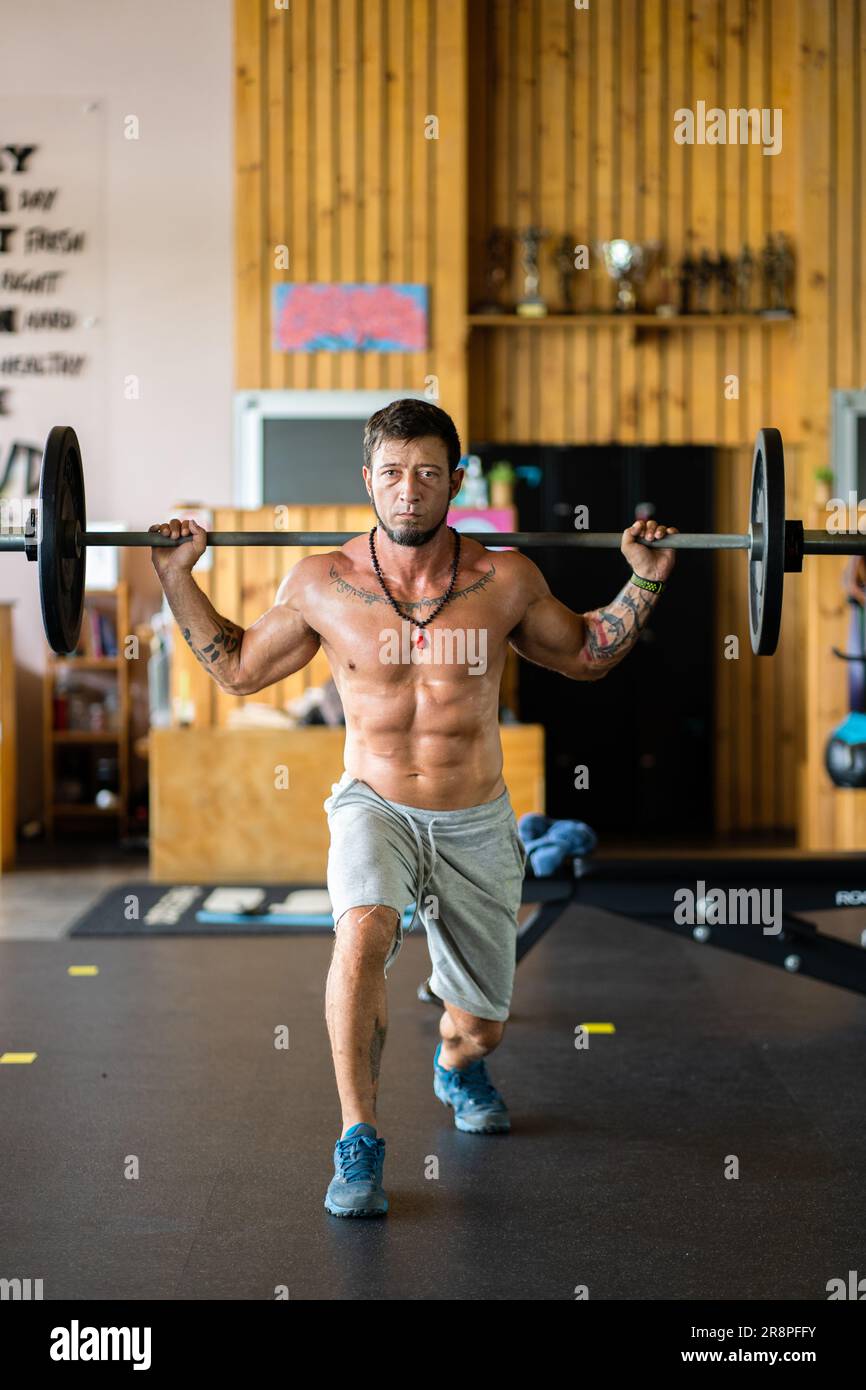 Fit man doing squats with weight using a bar in a gym Stock Photo - Alamy