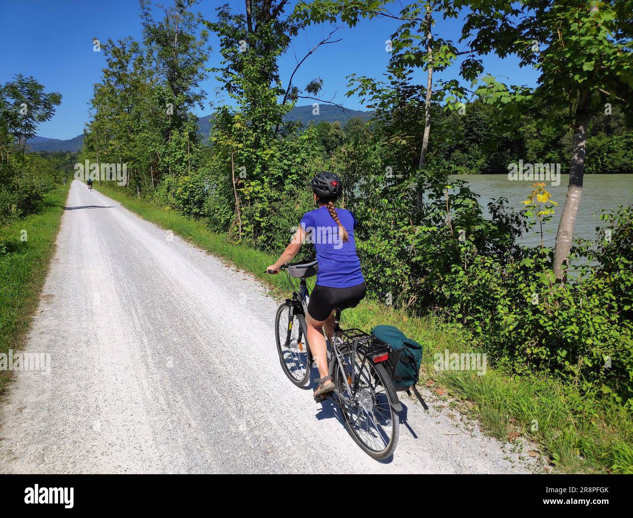 Female cyclist wearing helmet rides along river Salzach near Salzburg ...