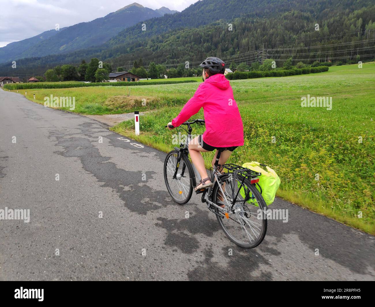 Female cyclist wearing helmet rides on Gailradweg long-distance bicycle ...