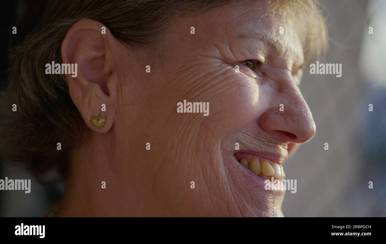 Profile close-up face of a happy senior woman smiling feeling joy and ...
