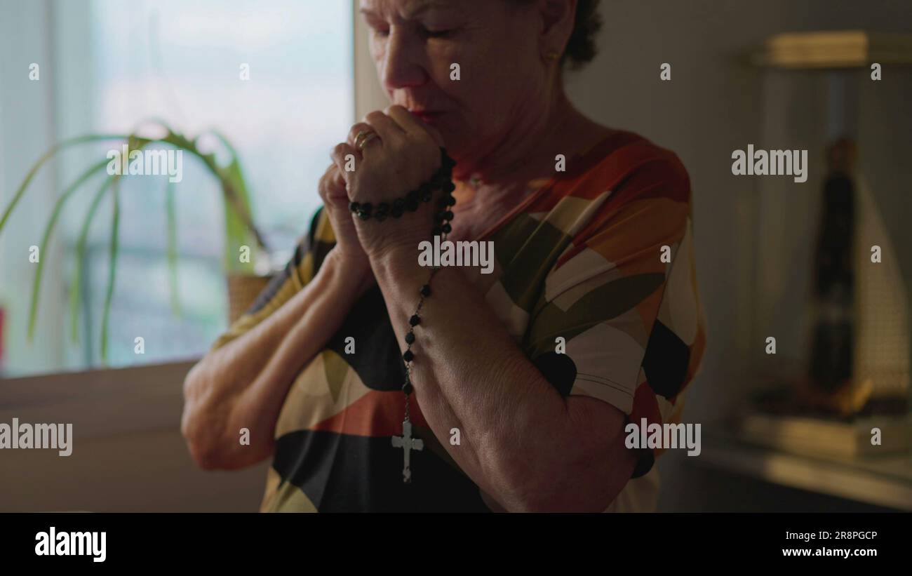 Religious Catholic older woman Praying Rosary at home in deep ...