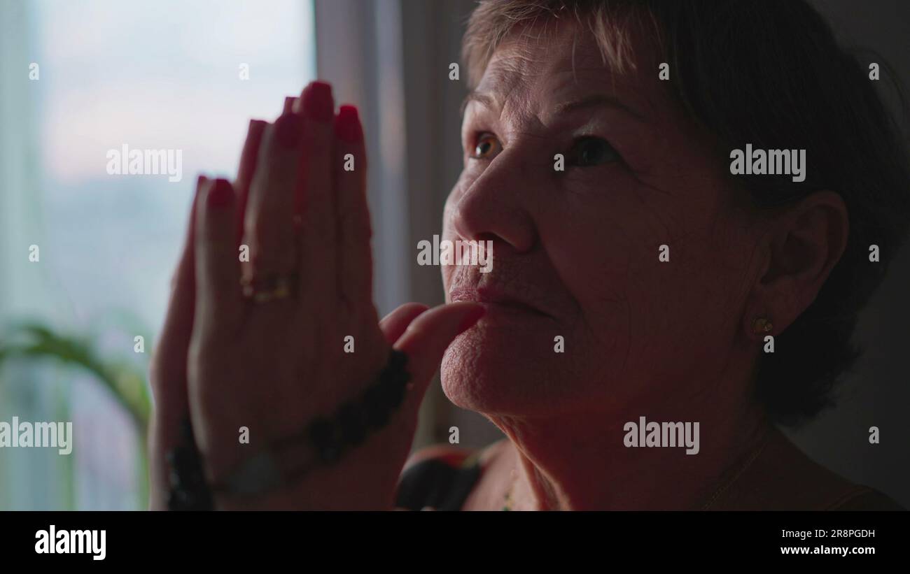 Religious older woman Praying Rosary at home closing eyes in ...