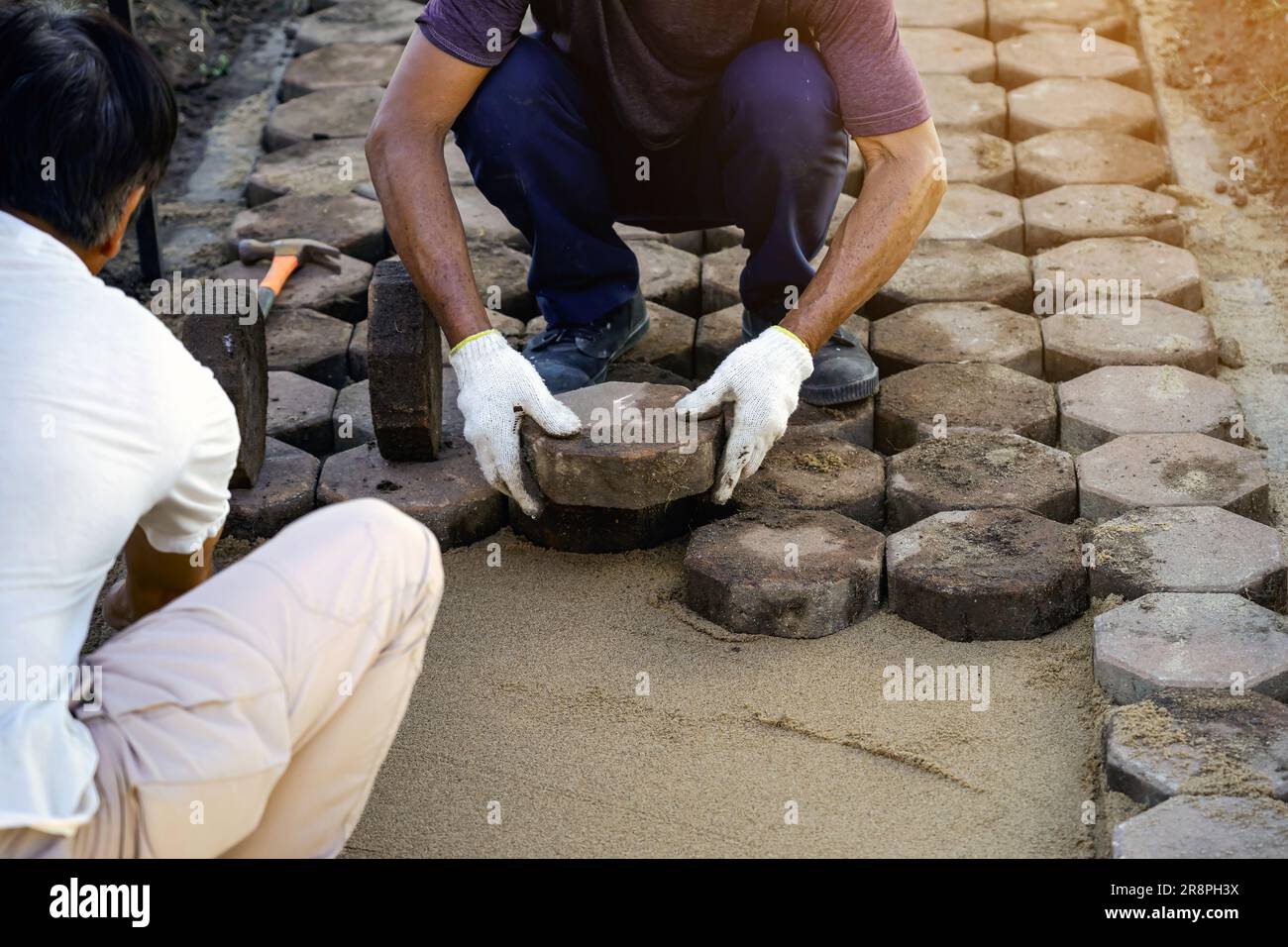 Hands of workman make it fit and to place stone pavers in a row ...