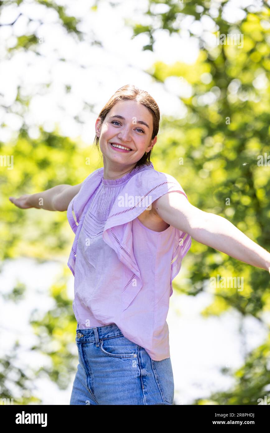Young woman with her arms wide spread is enjoying in the sunny summer ...
