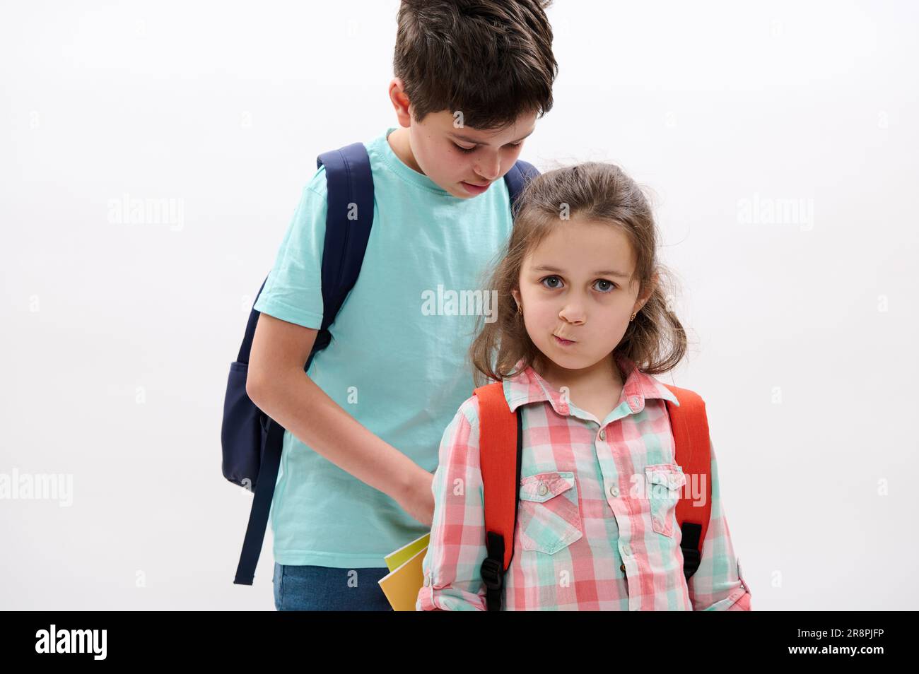 Mischievous kid girl makes faces at camera while her brother puts ...