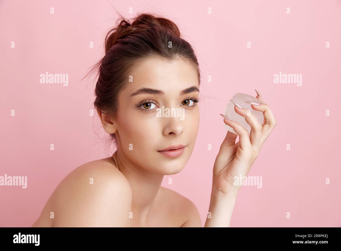 Young beautiful woman taking care after her perfect skin with ice cube ...