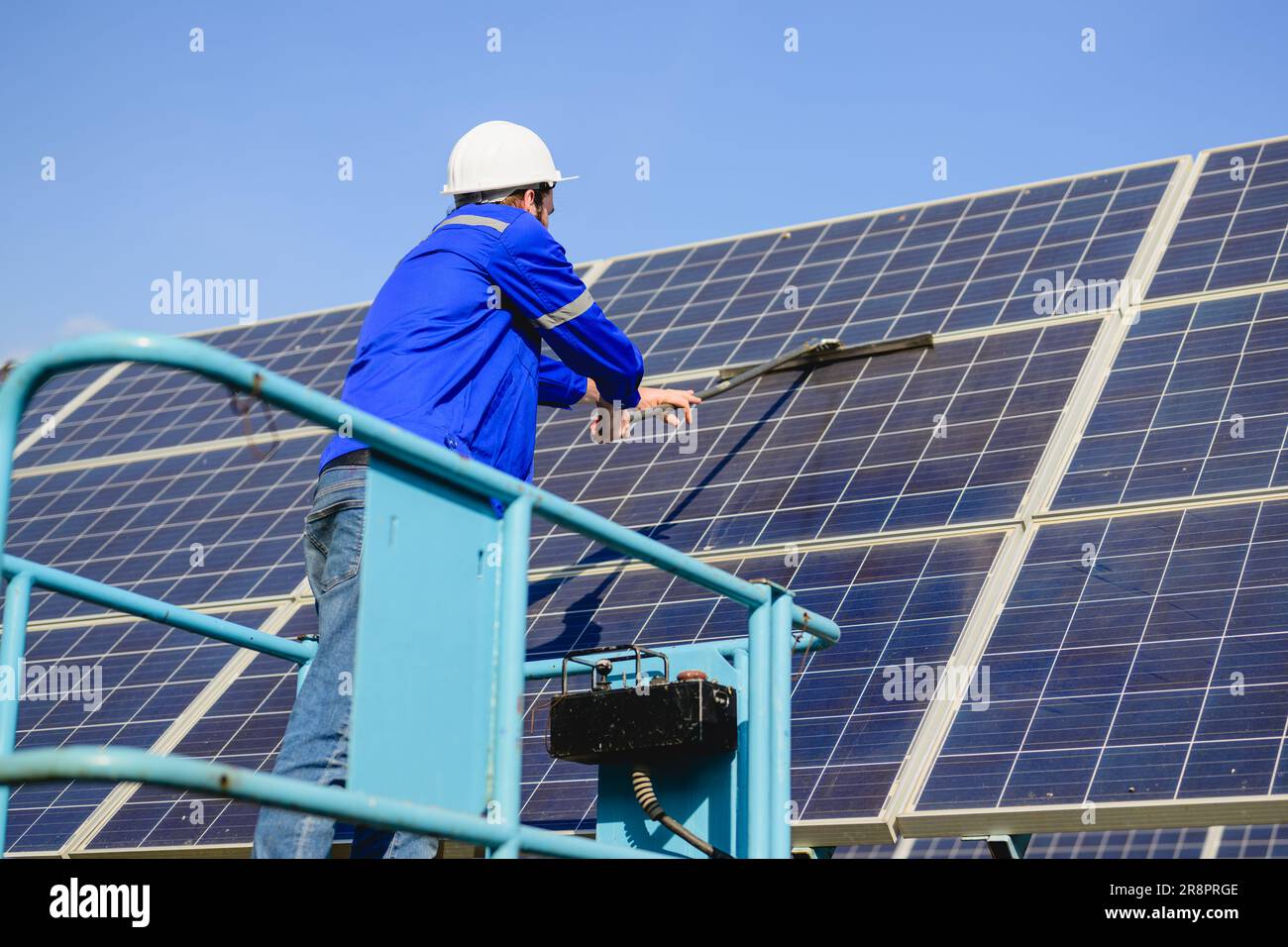 Maintenance worker cleaning solar panels at industrial solar cell farm ...
