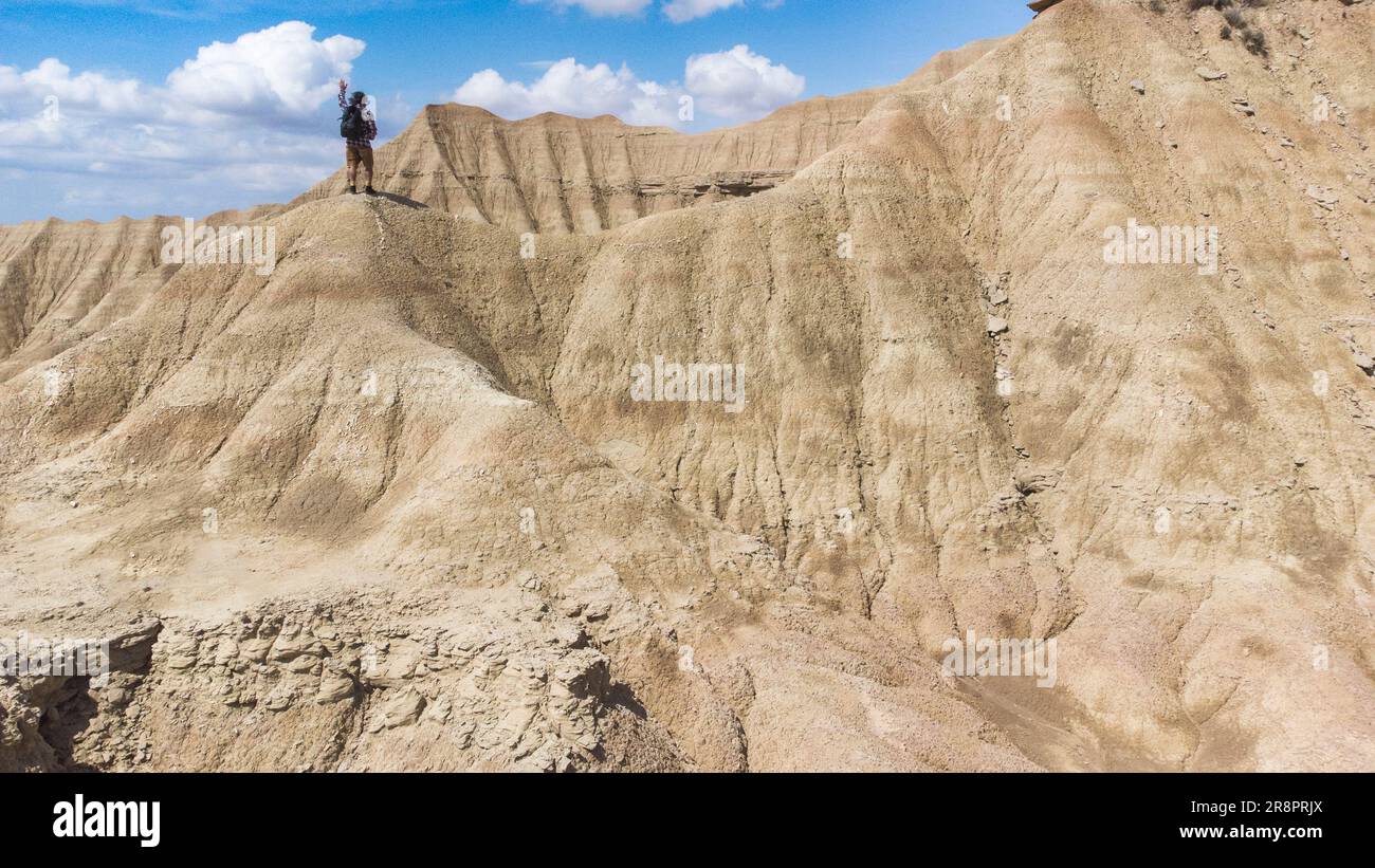 A backpacker standing on top of the rocky dunes enjoying the desert ...