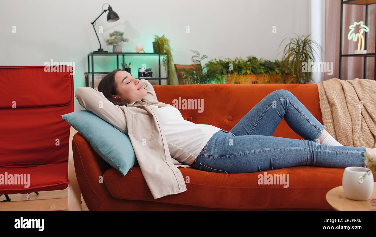 Portrait of tired young woman enjoy relaxing on home sofa in room ...