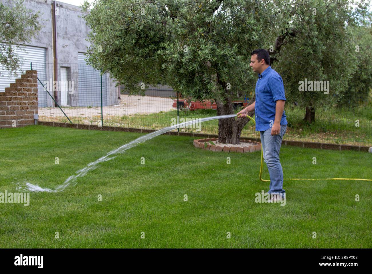 Image of a man watering his garden with a hose. Lawn care and ...