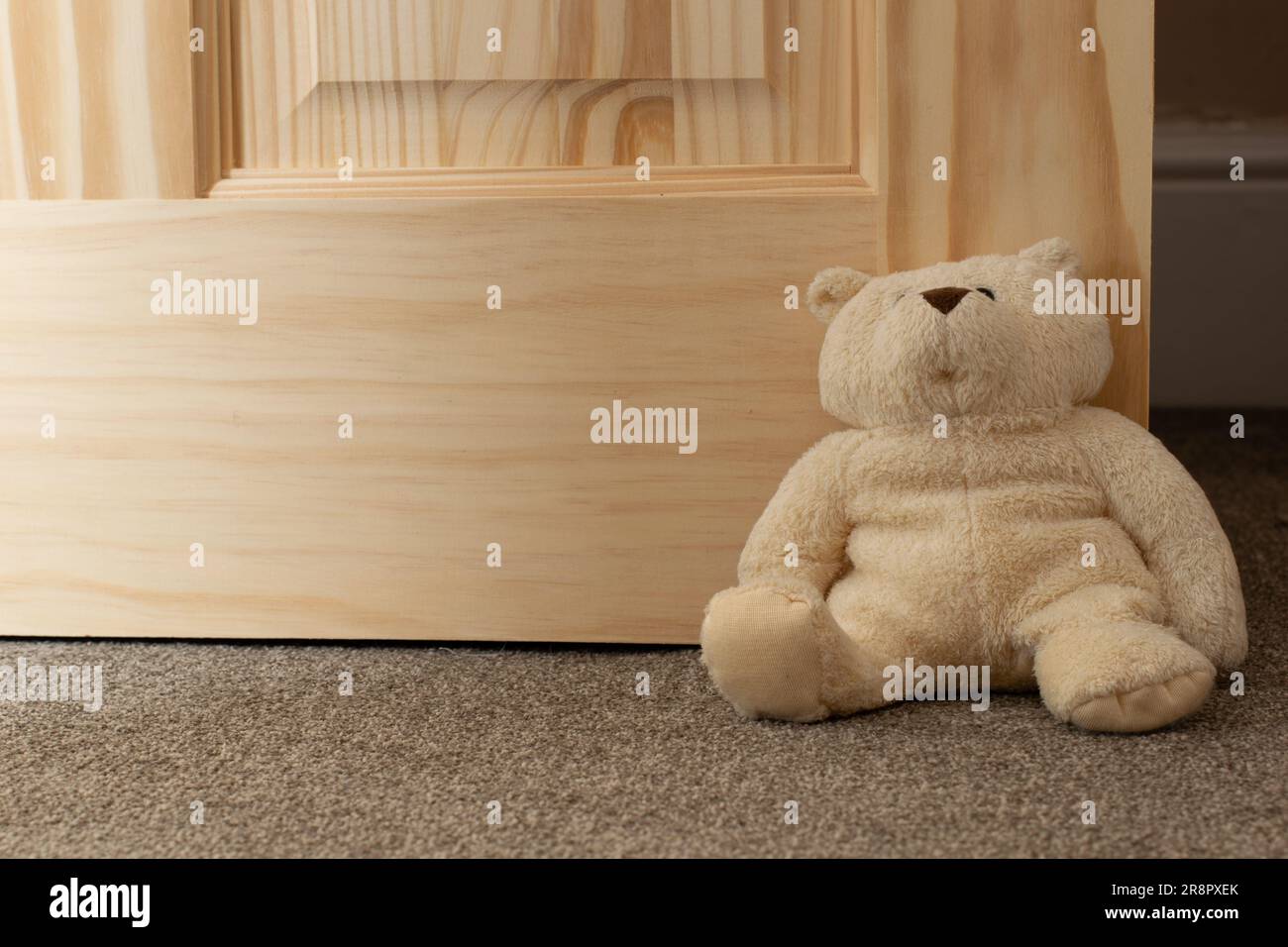 Teddy bear soft toy used to prop open pine panel door for house viewing ...