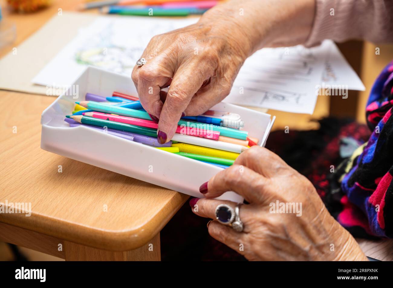 Elderly woman painting color on her drawing. Hobby at nursing home ...