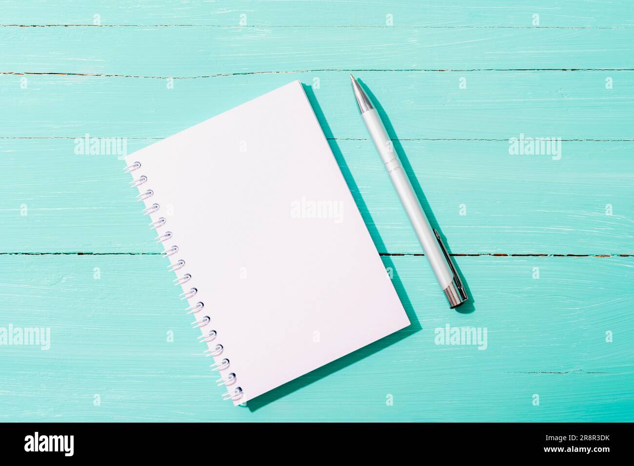 Notepad and pen on turquoise blue table in sunlight. Top view, flat lay ...