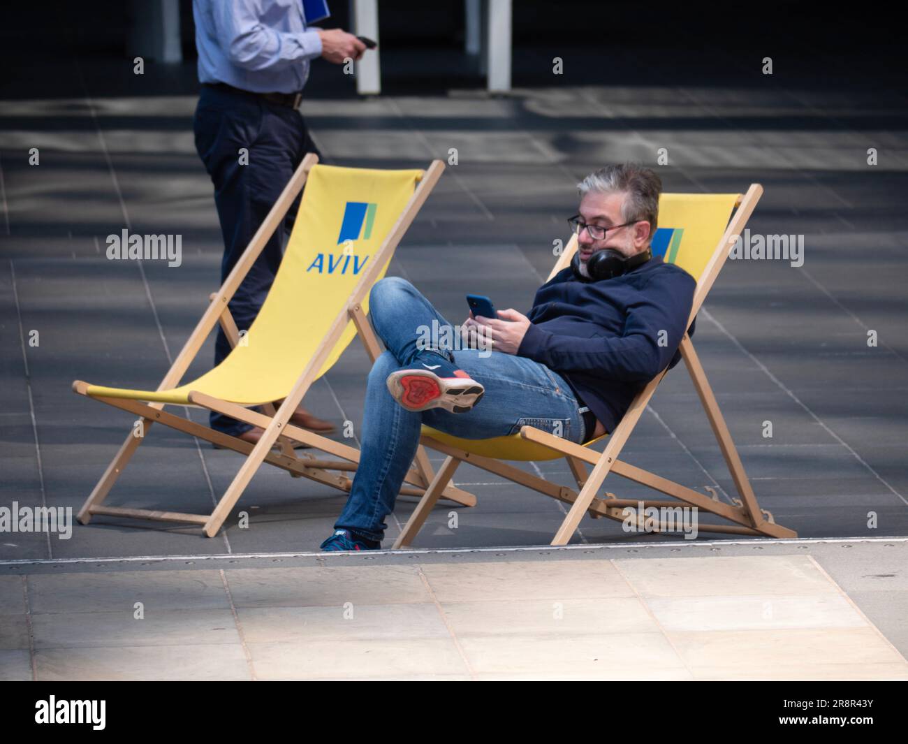 office workers sit in the sun on Aviva deckchairs outside the Aviva ...