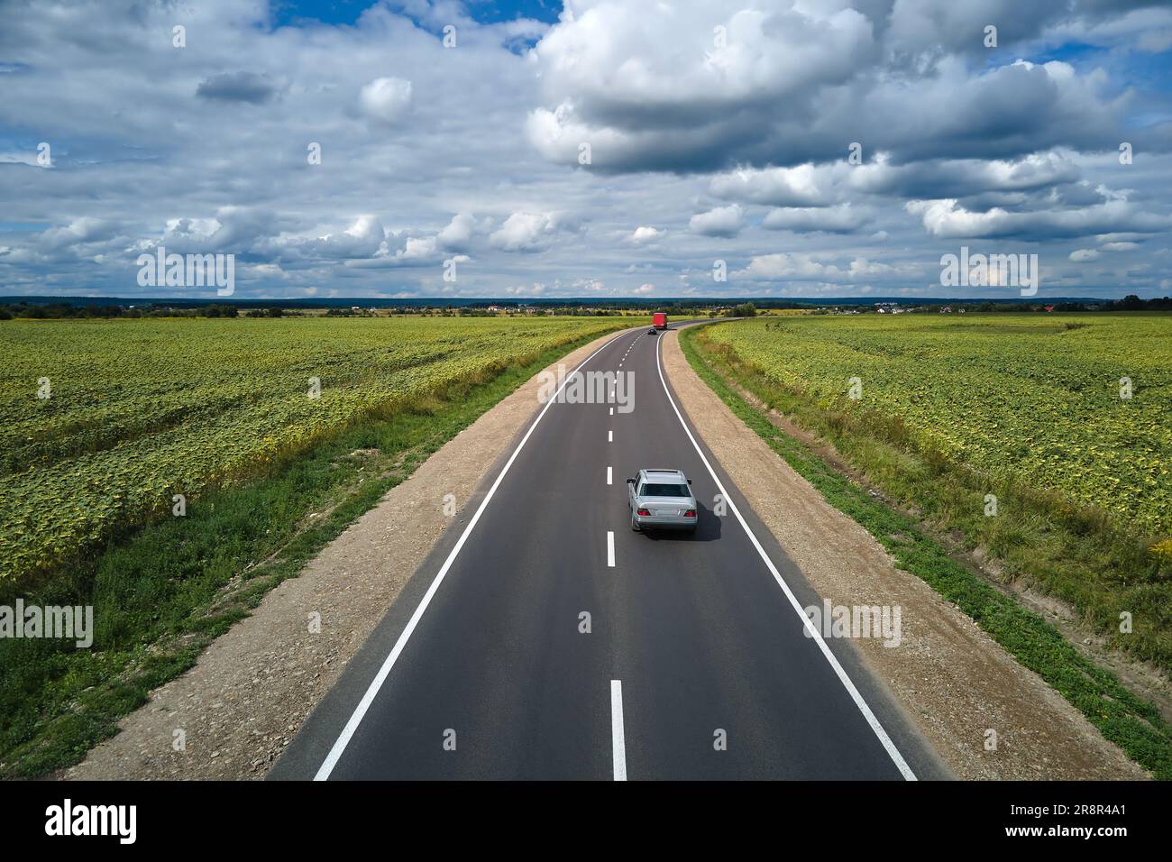 Aerial view of intercity road between green agricultural fields with ...