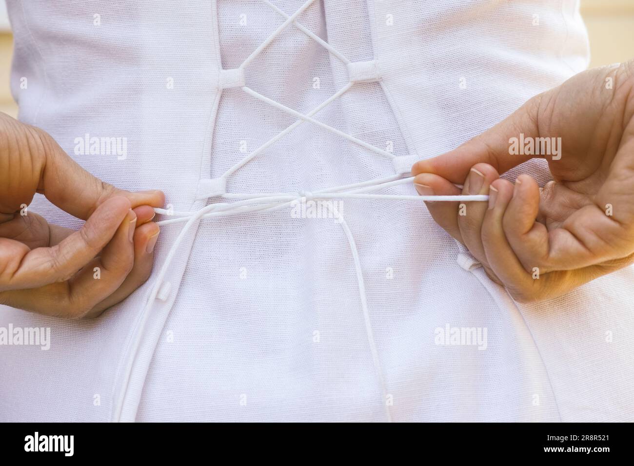 A girl tightening laces on the back of her dress Stock Photo - Alamy