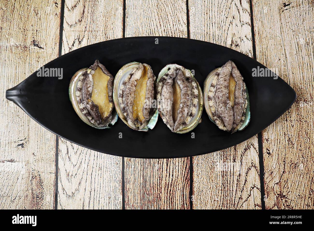 A live abalone on a black plate Stock Photo - Alamy