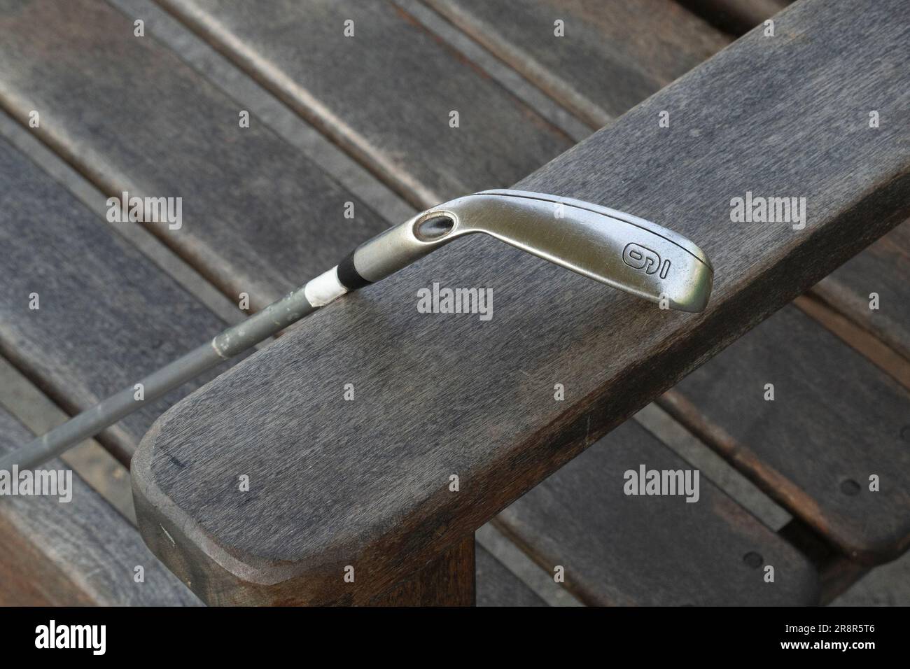 A nine iron golf club leaned on a wooden bench Stock Photo - Alamy