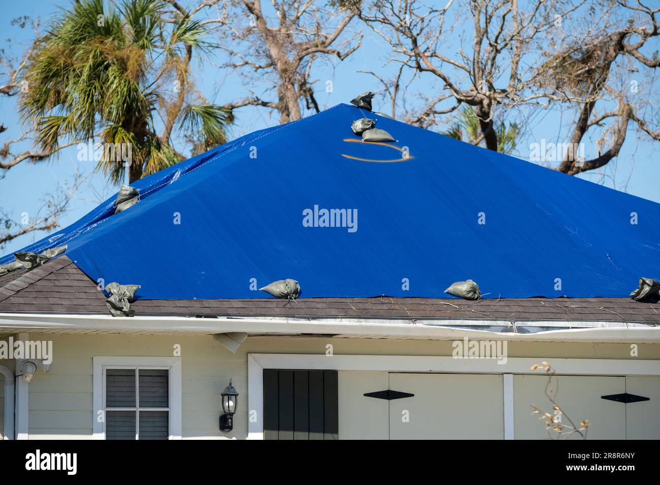 Leaking house roof covered with protective tarp sheets against rain ...